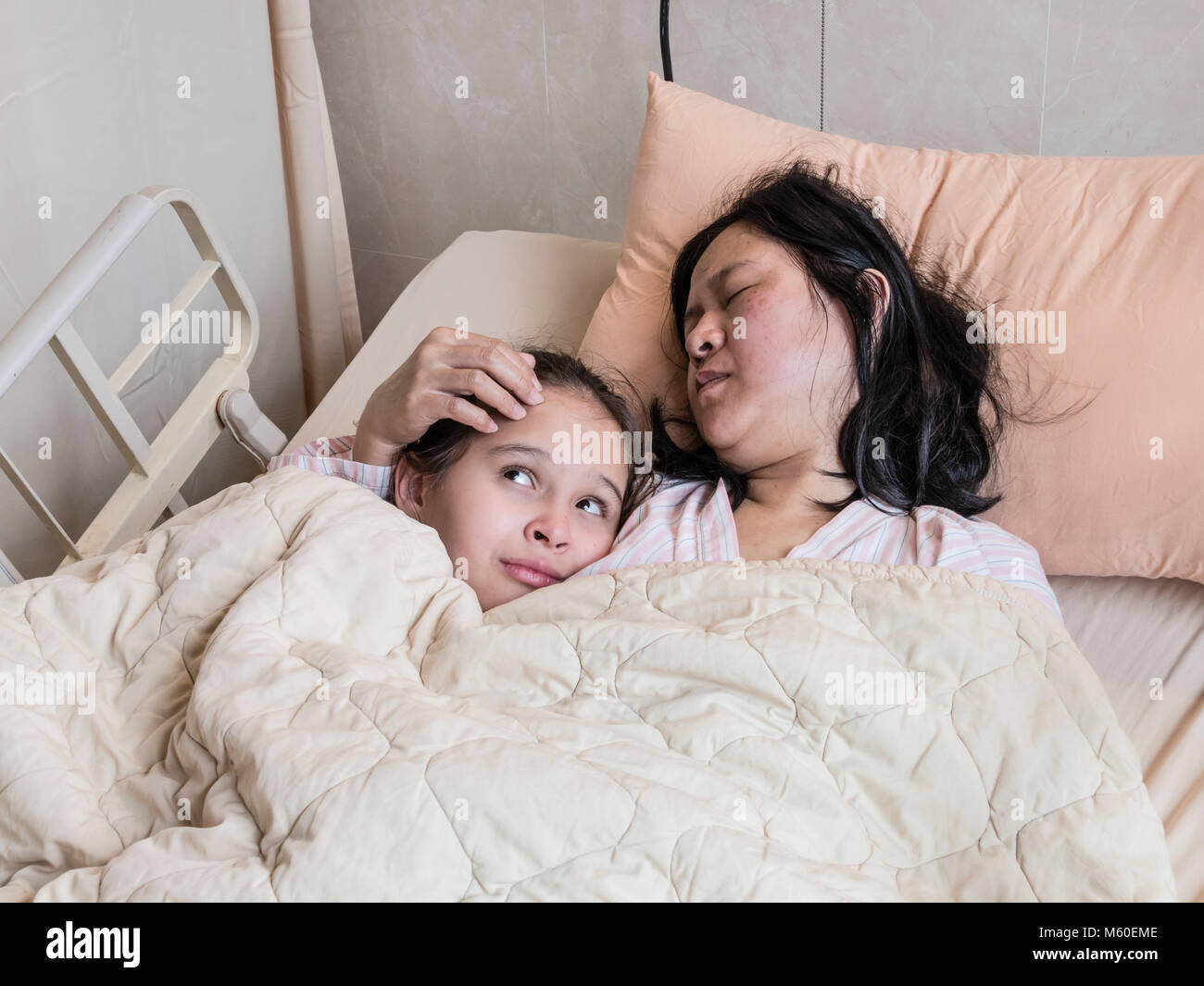 Girl lying on hospital bed next to sick mother, family health care ...
