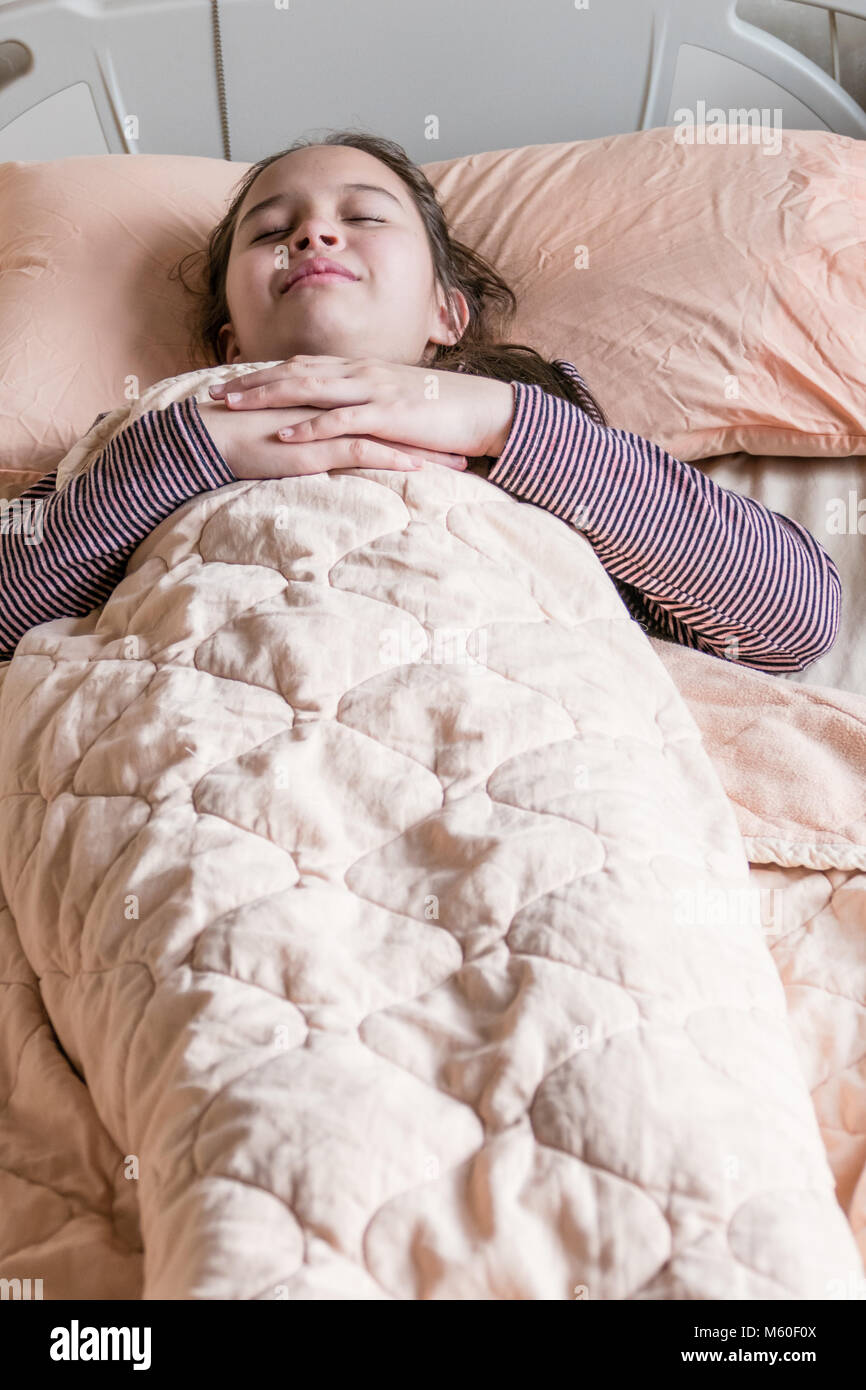 Asian American tween girl lying in hospital bed, health care concept ...