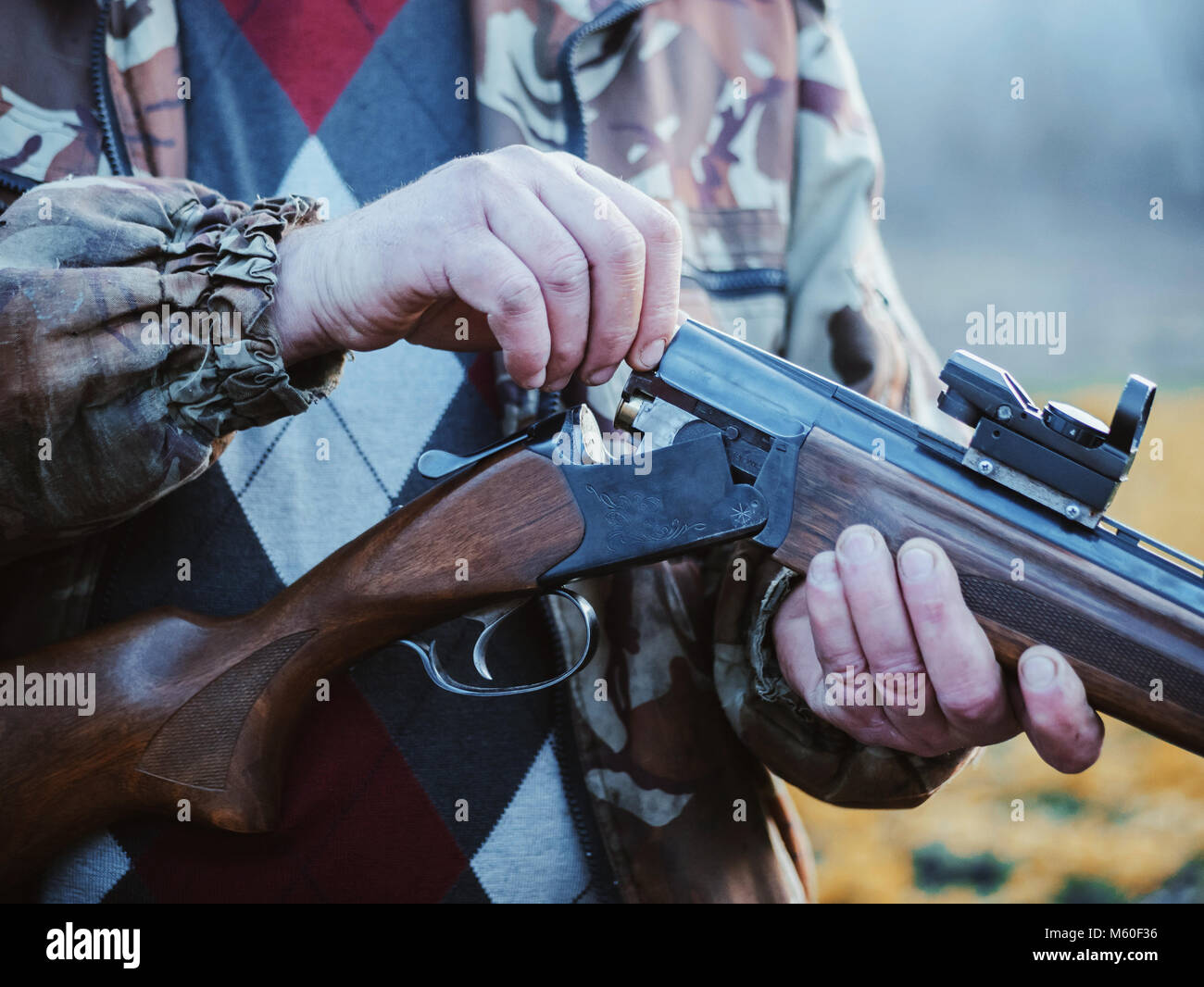 Sports shooting. Hunter reloading cartridge in field. Smoke from the ...