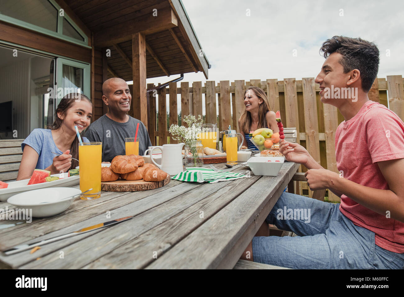 Family sitting outside holdiay lodge and eating breakfast Stock Photo ...