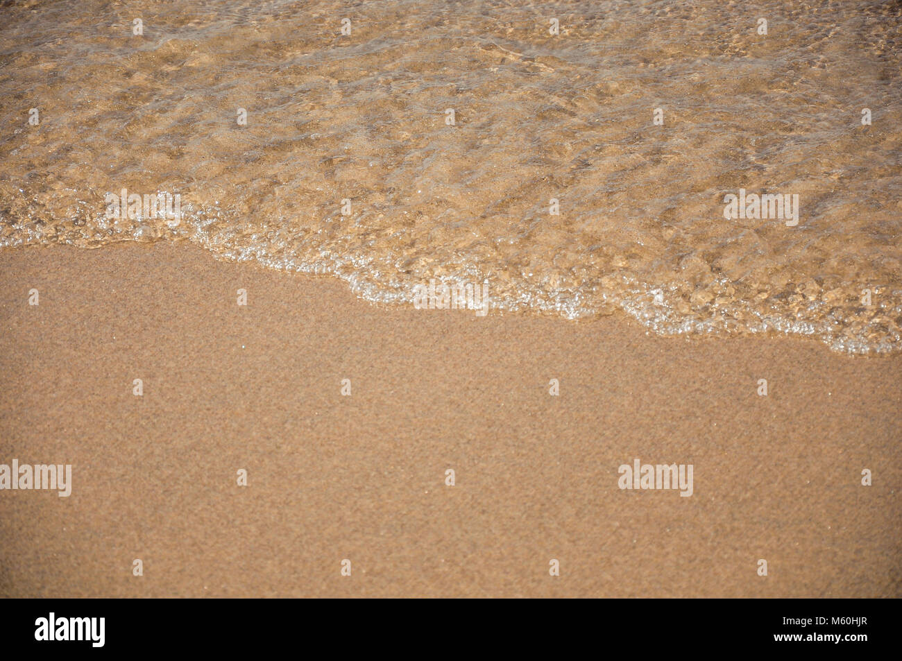 Sea water breaking on the sand with sunshine at the beach of Juquey, an ...