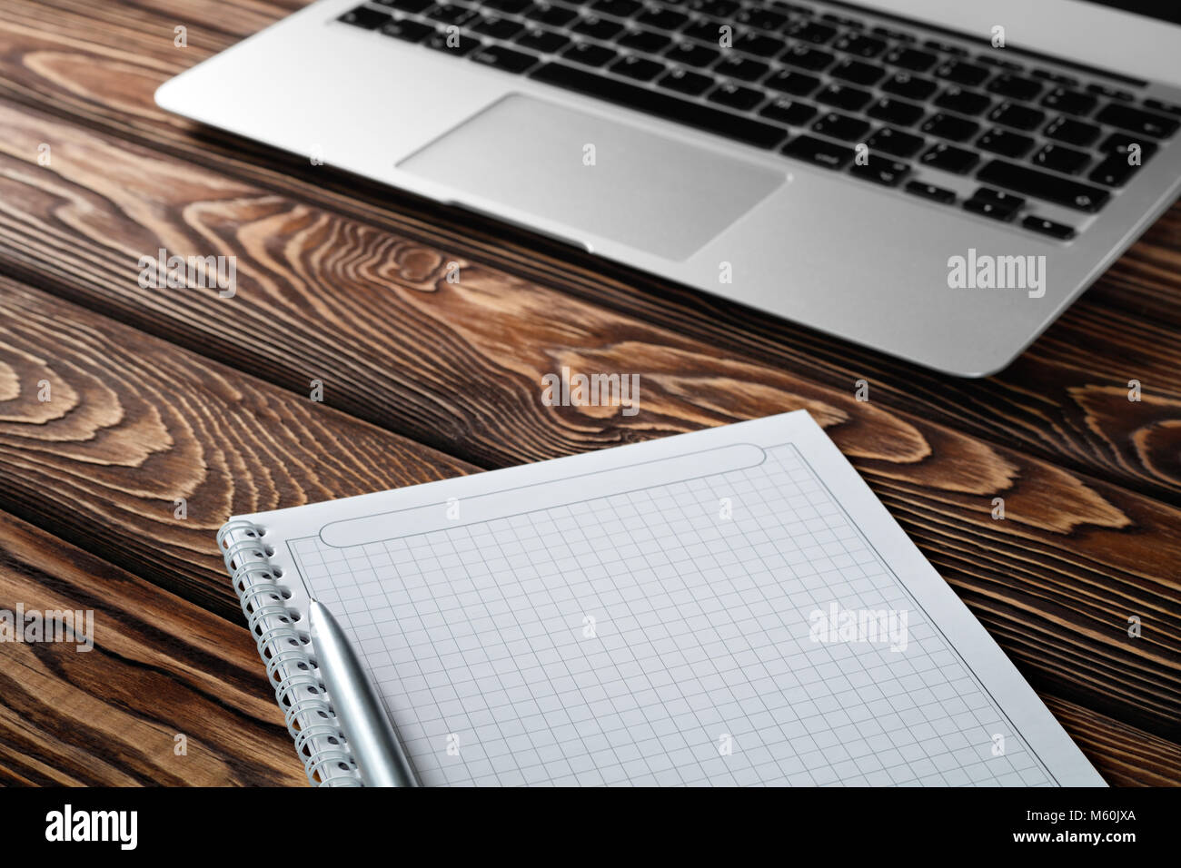 Notepad, laptop and pen on wood texture table, start of Morning work ...