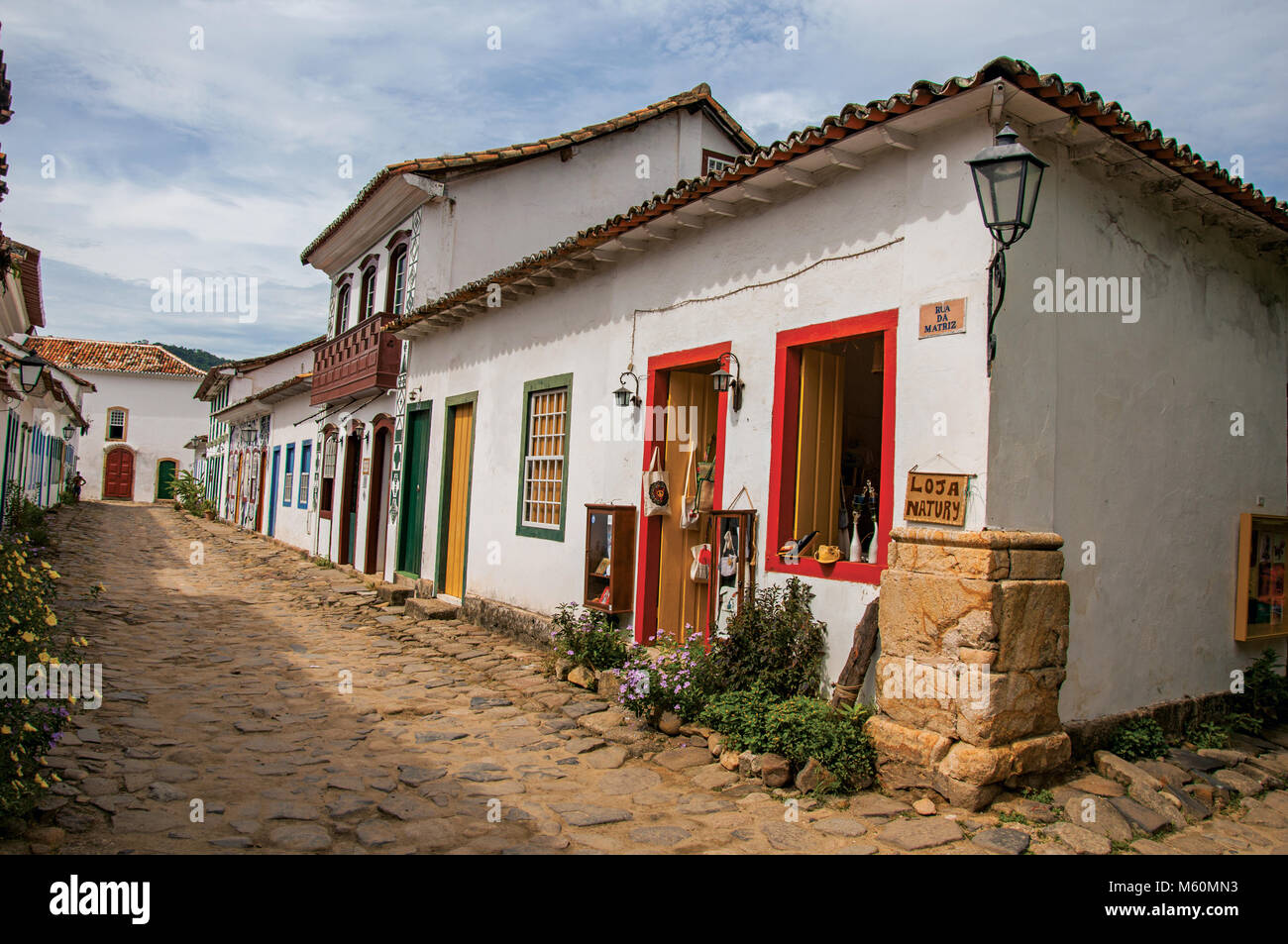 Paraty, Brazil. Cobblestone street with old houses under blue cloudy ...