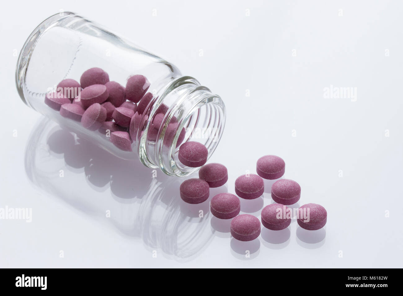 purple tablets spilled out from a glass bottle Stock Photo - Alamy