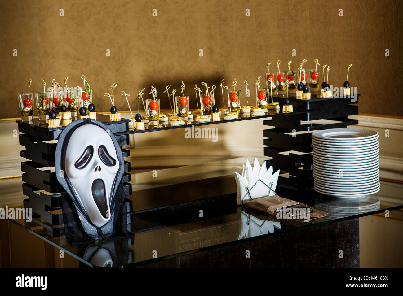 cheese snack, plates, cutlery, scary mask arranged on glass table on ...