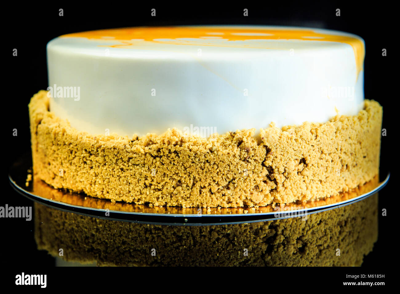 whole white musk cake coated with white and yellow glaze on black ...