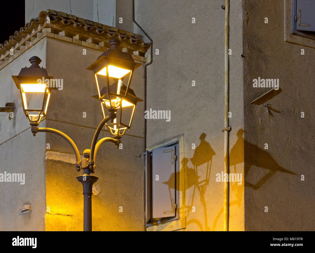 Streetlamps casting their shadow on a historic building in Grado, Italy ...