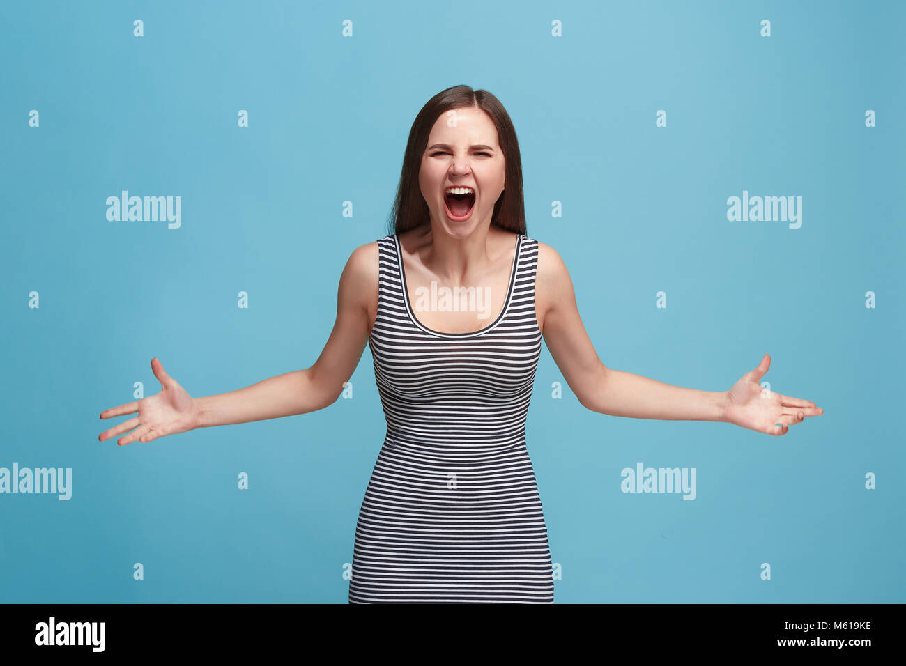 The young emotional angry woman screaming on blue studio background ...