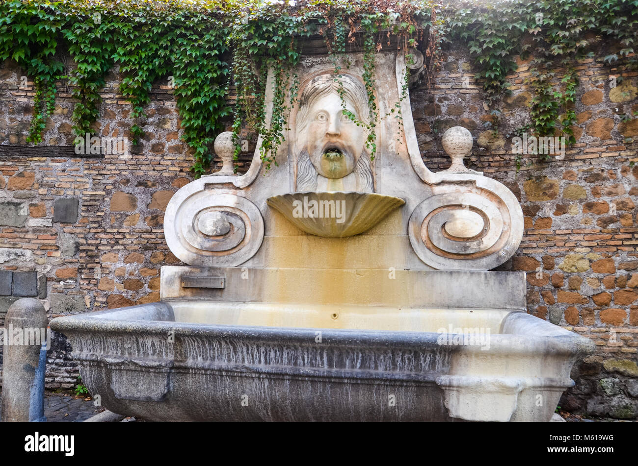 Drinking fountain with image of head in Rome Stock Photo - Alamy