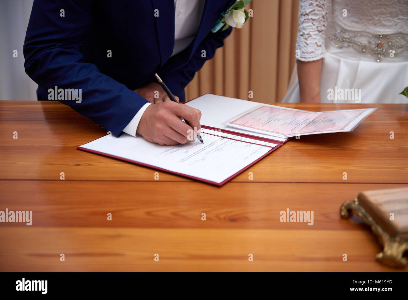 Close-up image of hands of newlywed couple signing marriage ...