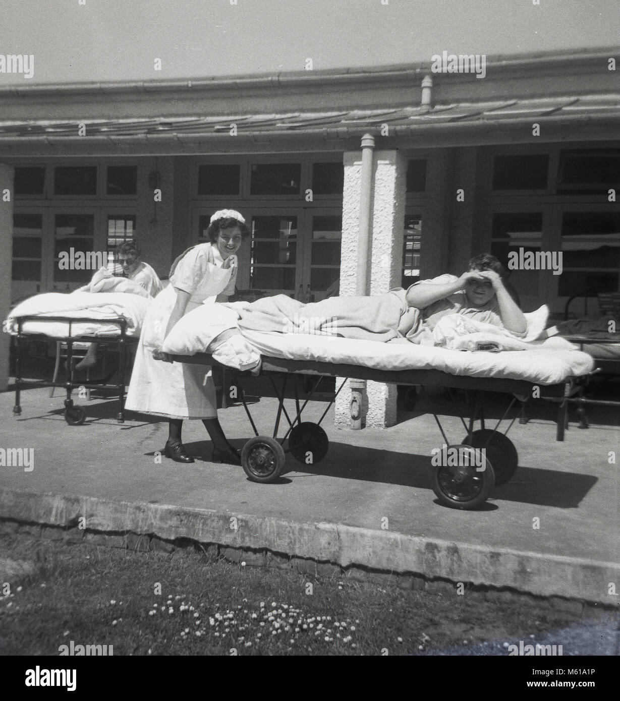 1940s, historical, England, a female nurse moving a young man lying on ...