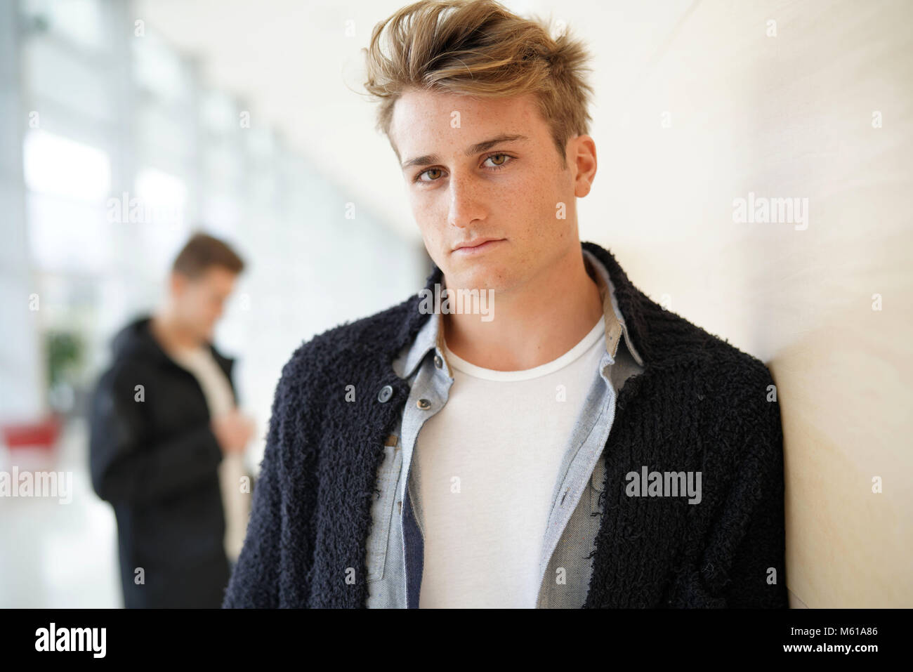 Young man standing in college hall Stock Photo - Alamy