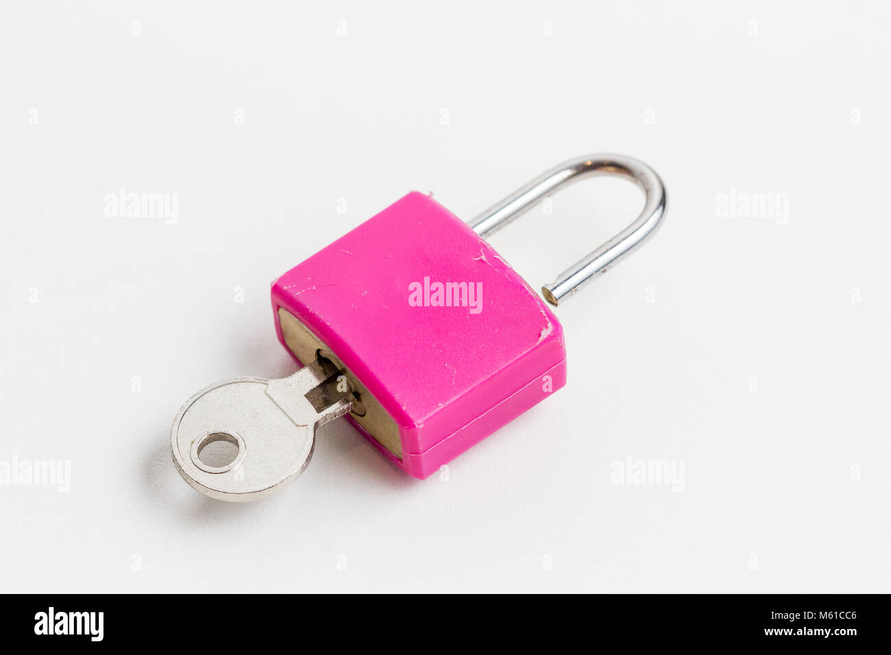 Pink luggage lock with key on white background Stock Photo - Alamy