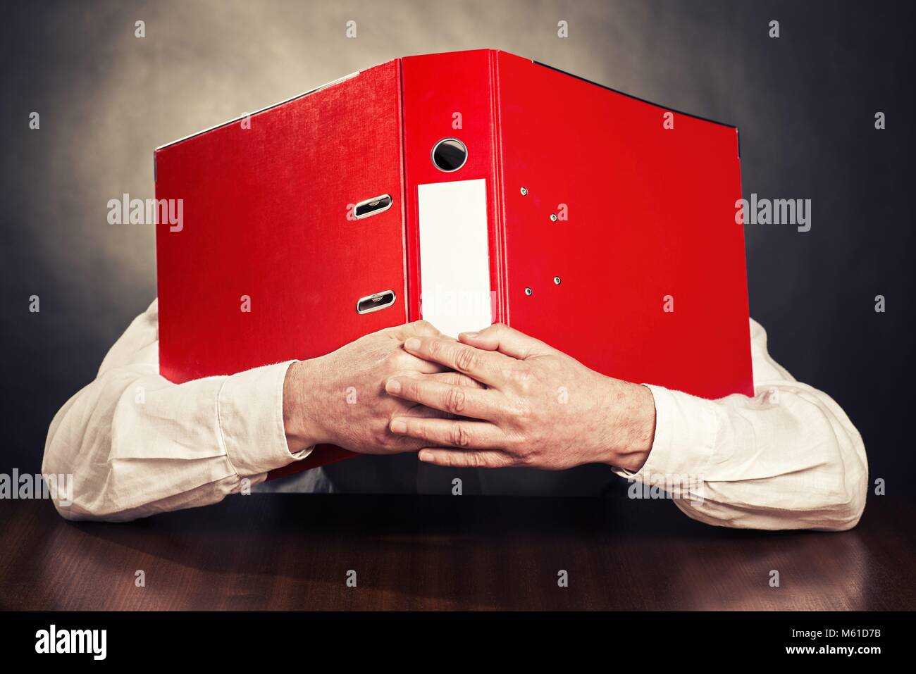 An employee hides his face behind a red file folder. | usage worldwide ...
