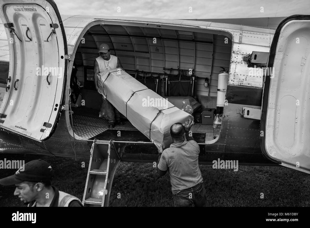 Airline workers load cargo (empty coffins) to a Douglas DC-3 aircraft ...