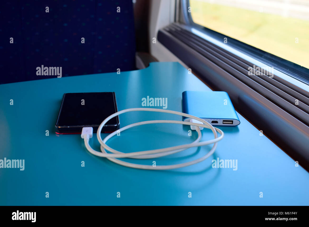 Black smartphone charging with blue power bank on blue table background ...