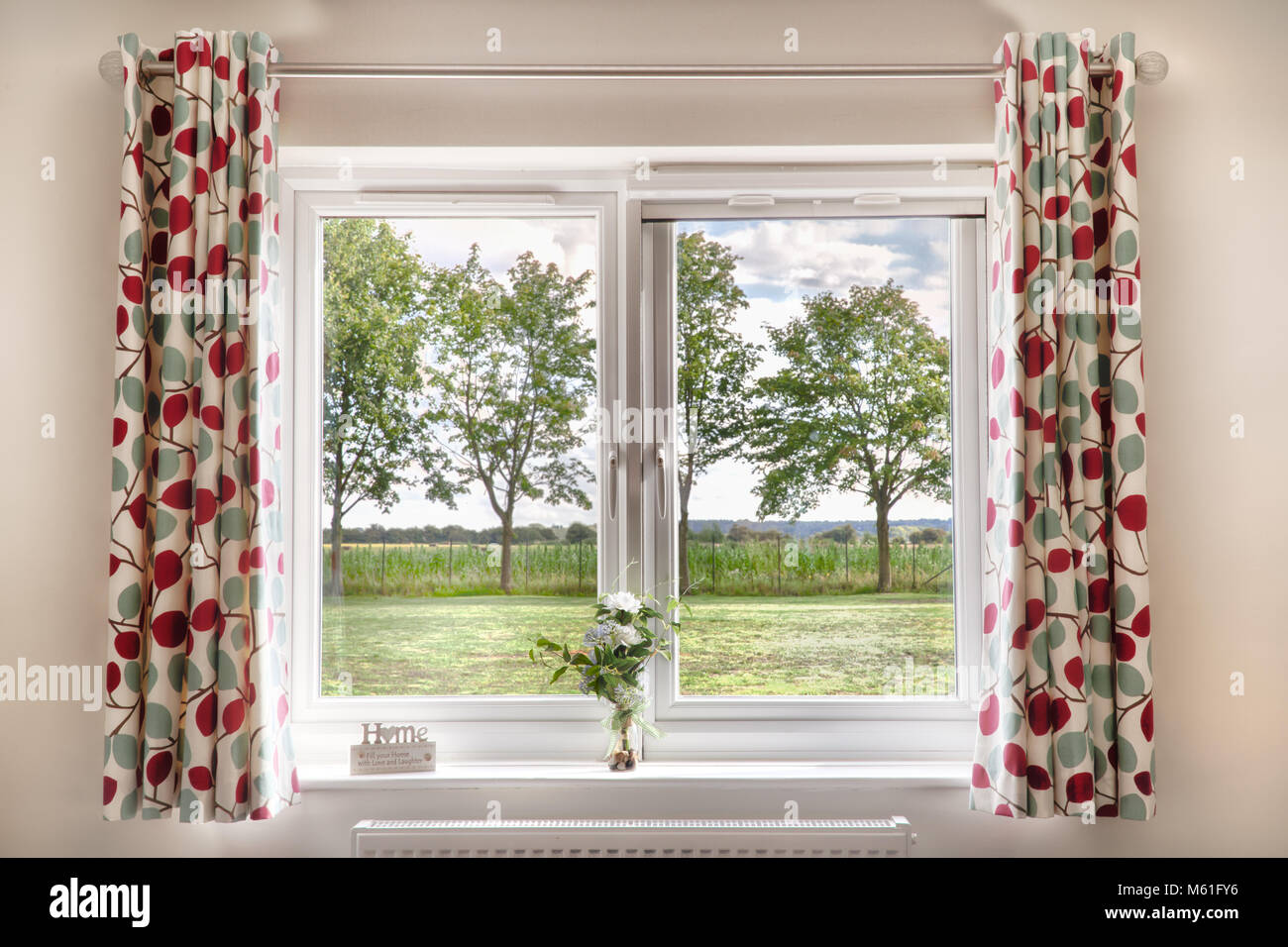 Window with a view onto fields and trees in a rural setting. Curtains ...