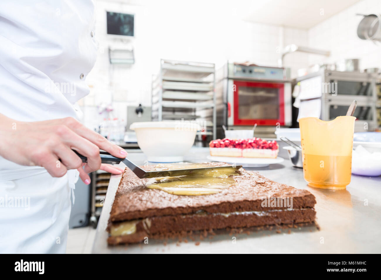 Confectioner woman getting chocolate cake ready with topping Stock ...