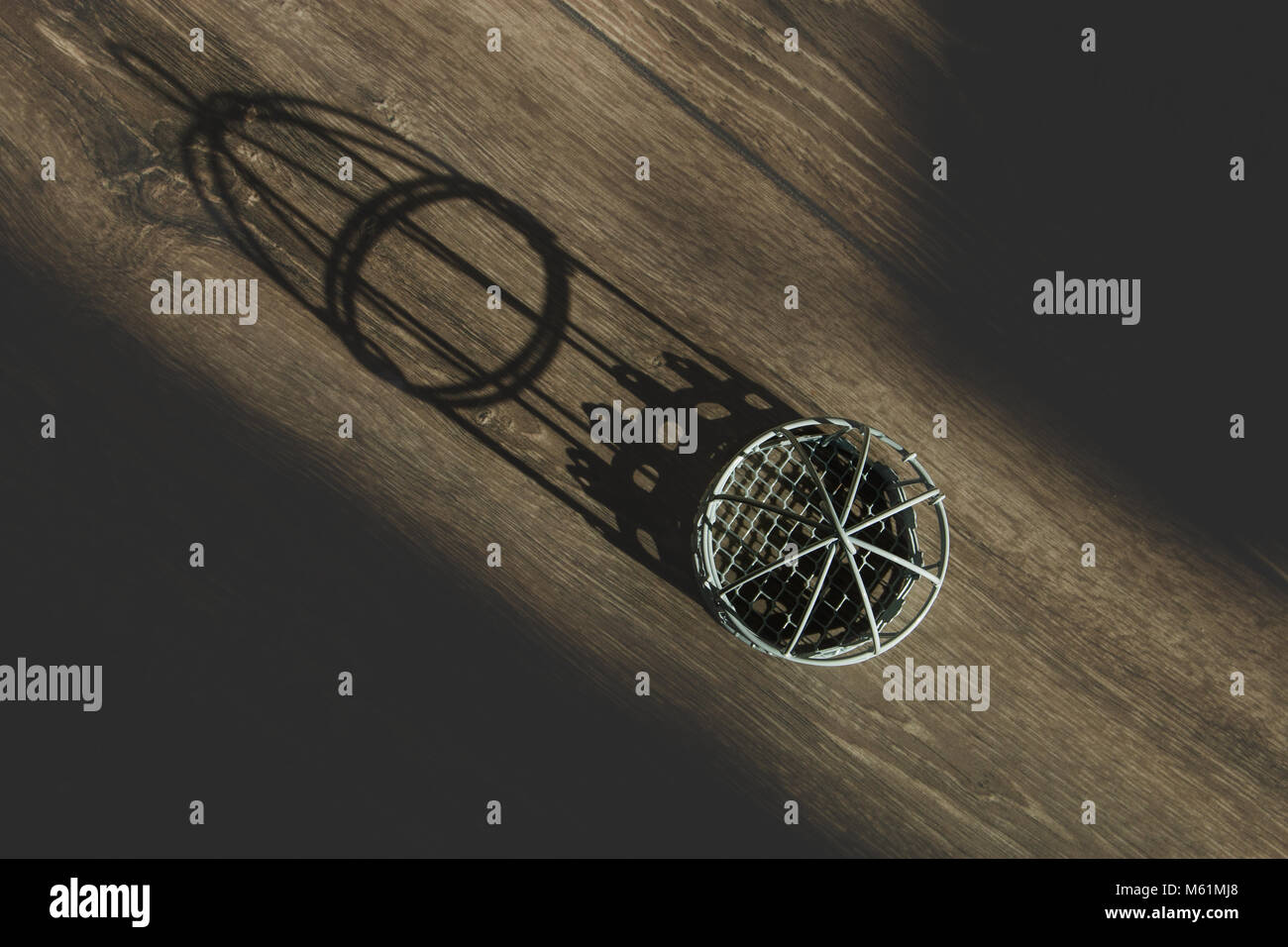 small decorative cage white on a wooden background and shadow from it ...