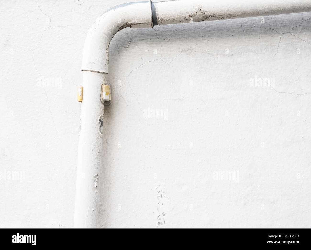 White PVC pipe for electrical wire on the white wall of the urban house ...
