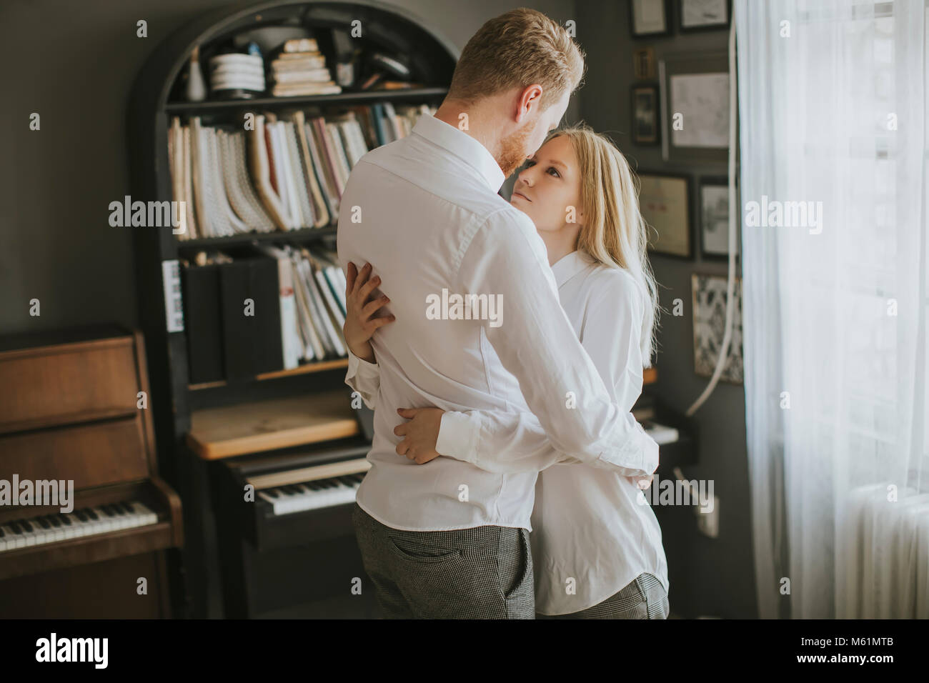 Loving young couple laughing, embracing and having fun in the room ...