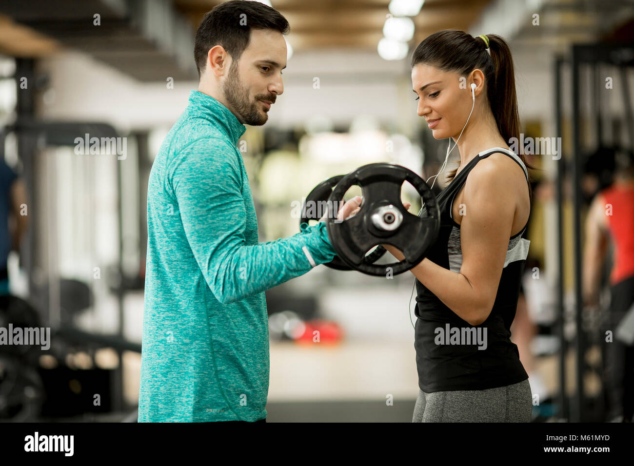 Young woman exercising with personal trainer in gym Stock Photo - Alamy