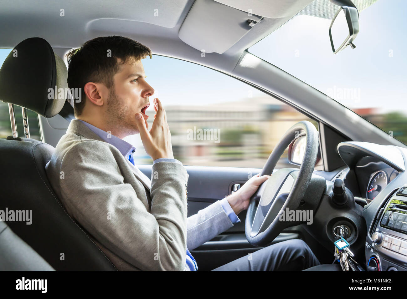 Side View Of A Young Man Yawning While Driving Car Stock Photo - Alamy