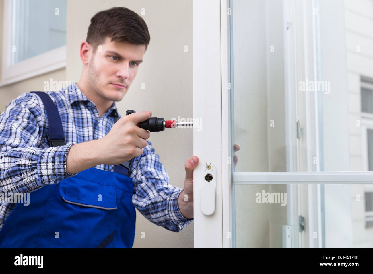 Male Handyman In Uniform Fixing Glass Window With Screwdriver Stock ...
