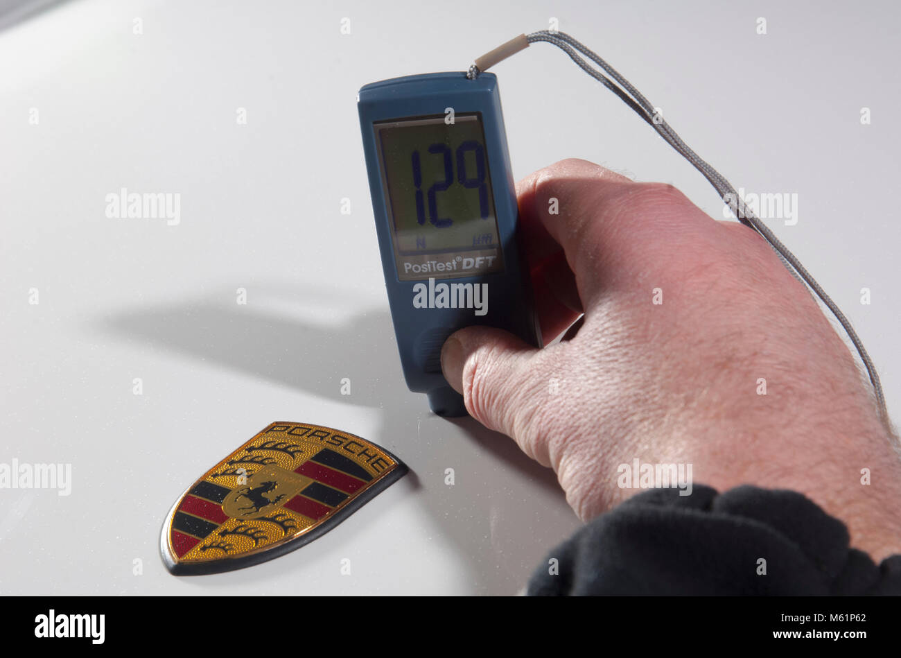 Car valeter measure paint depth while detailing a Porsche sports car ...