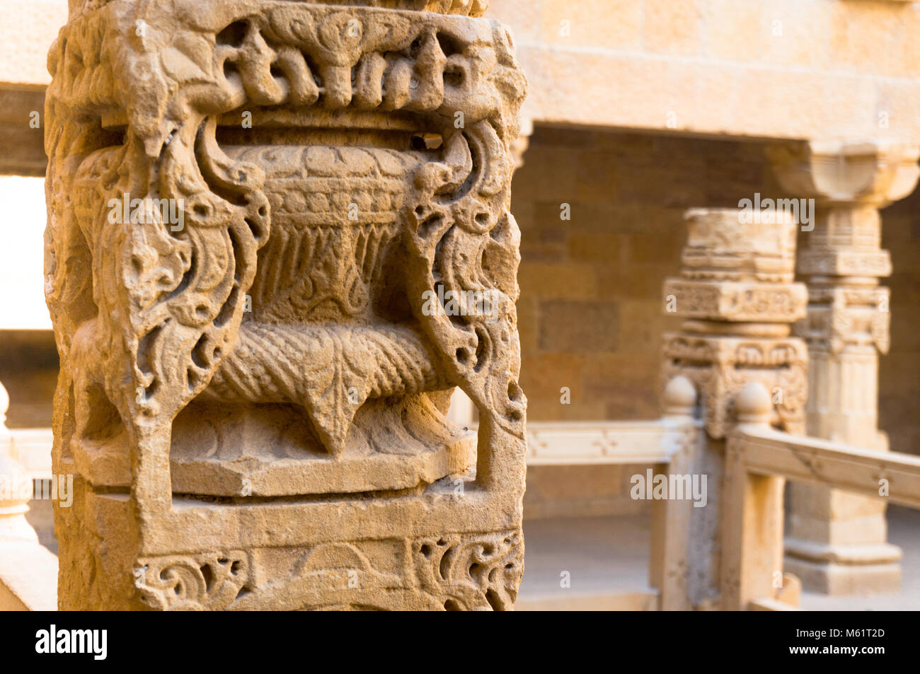 Beautifully carved ancient sandstone pillar with more pillars in the ...