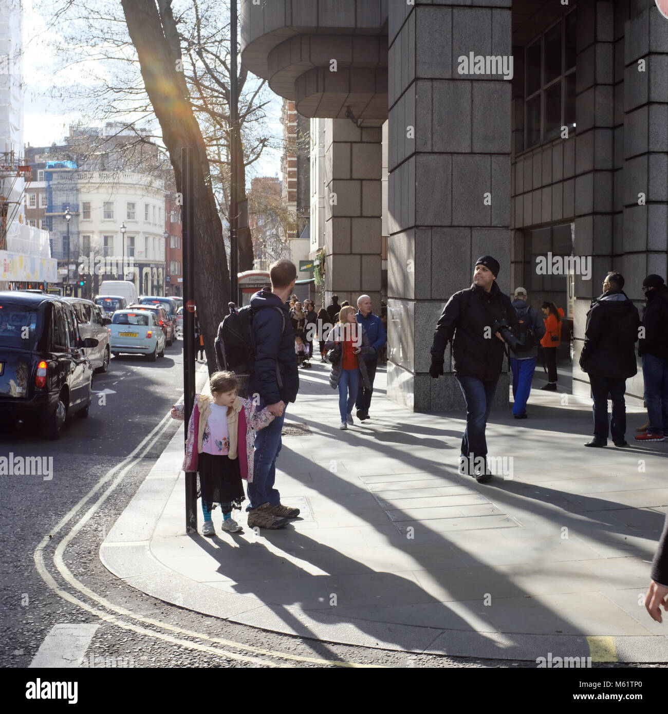 Man holding young girls hand waiting on street corner, Oxford street ...