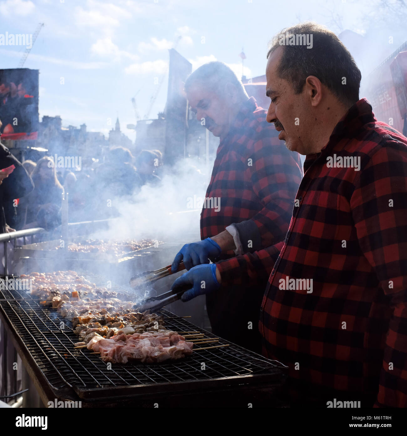 Men tending to meat on barbecue at Trafalger square during Chinese new ...
