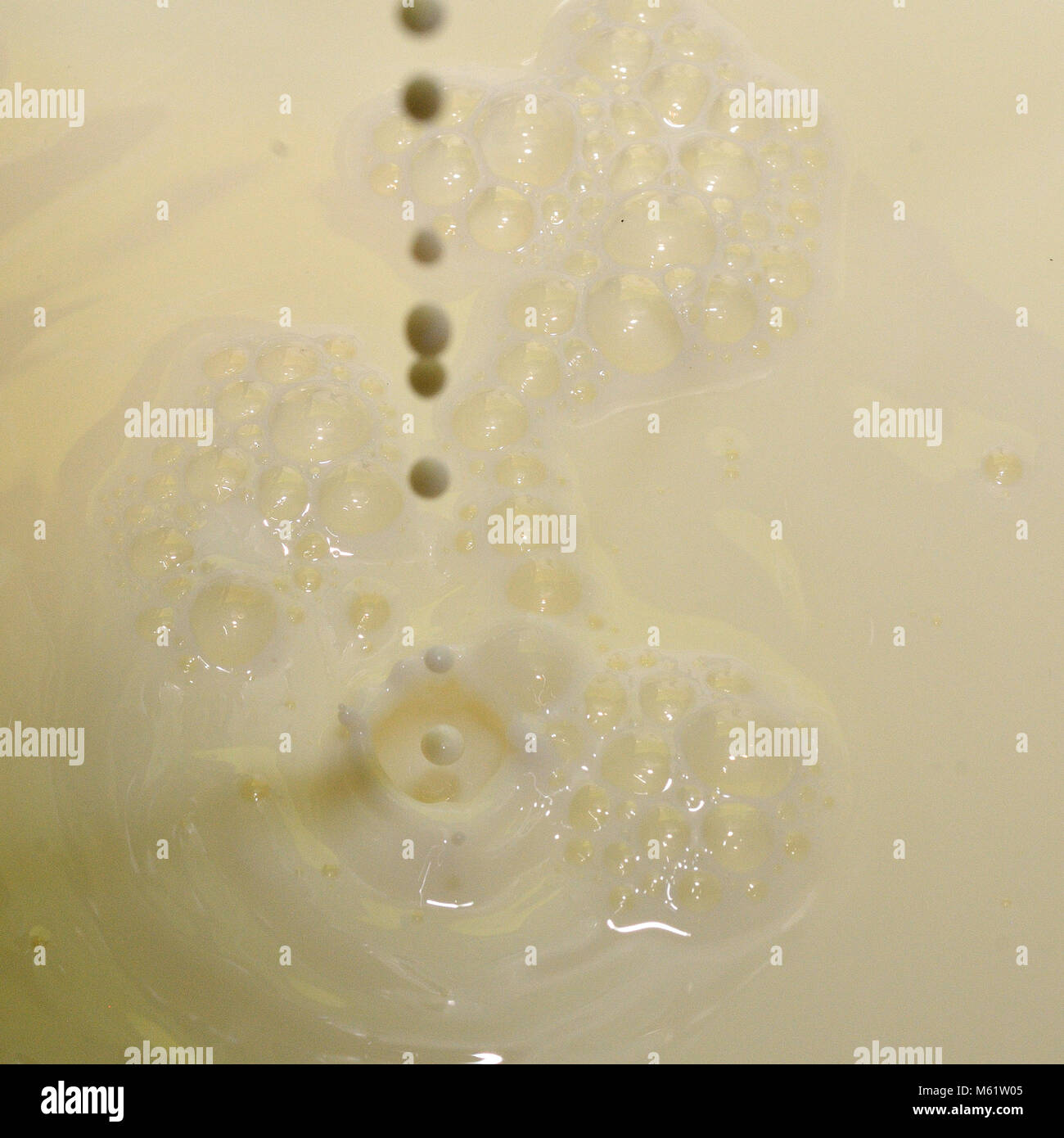 Milk drops falling splashing on milk surface Stock Photo - Alamy