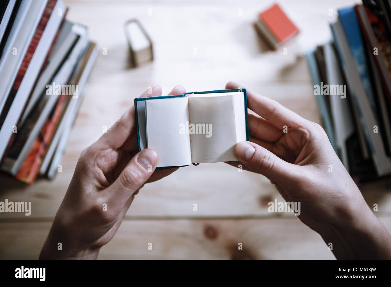A man reading a miniature book among the big books in the library Stock ...