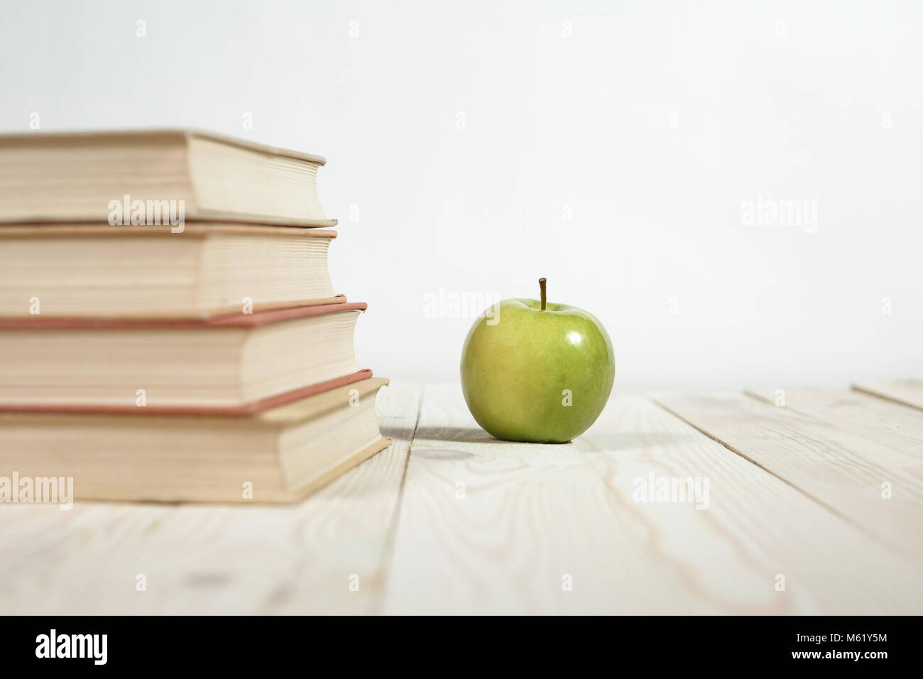 Stack of books and apple on the table Stock Photo - Alamy