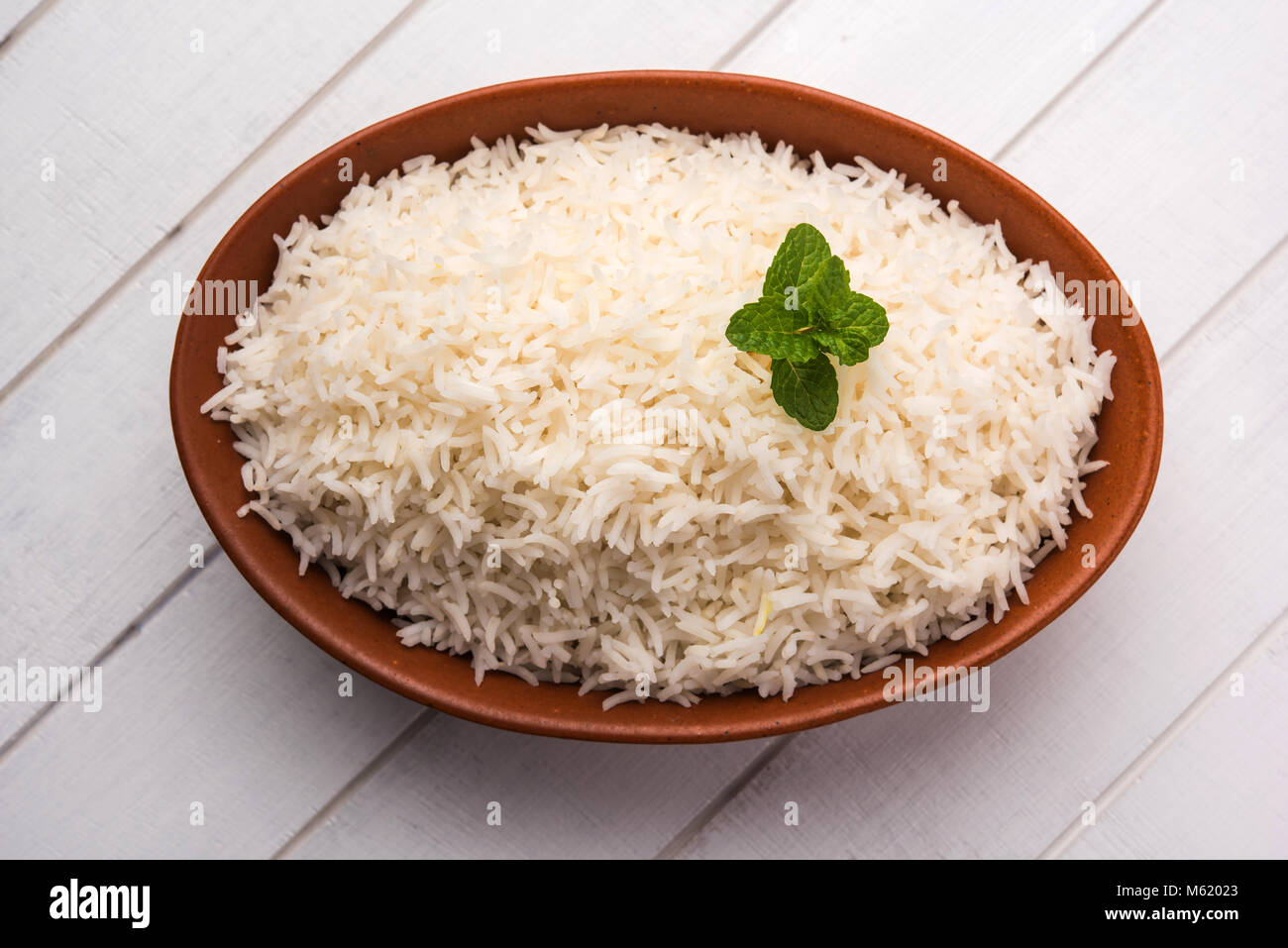 Cooked plain white basmati rice in terracotta bowl over plain or wooden ...