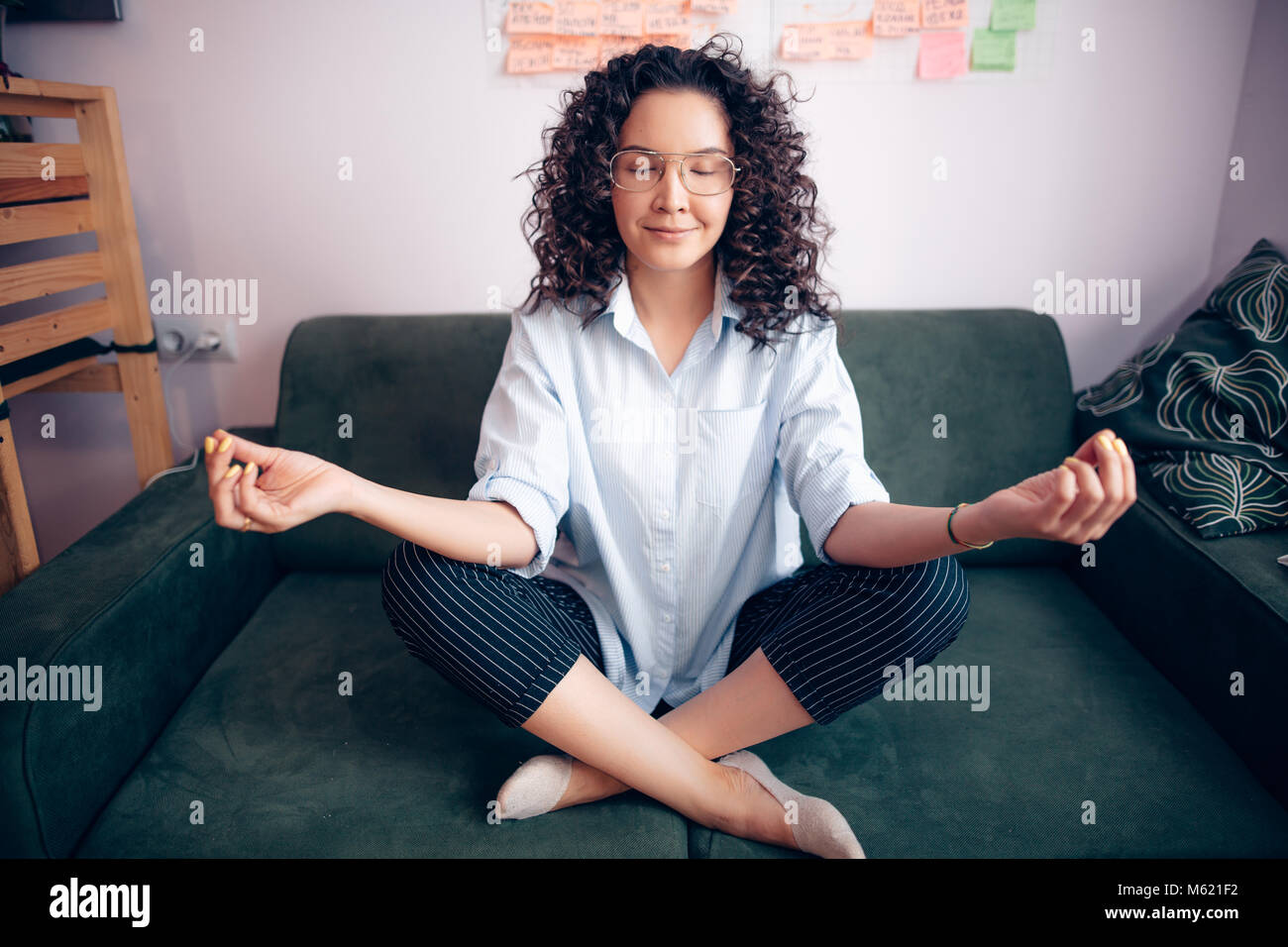 Beautiful woman sitting on coach in lotus pose of yoga Stock Photo - Alamy