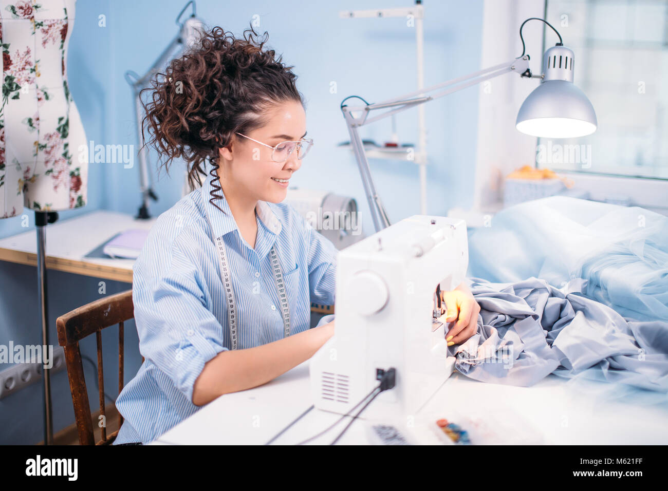 tailor wearing blue blouse and having flexible ruler on her shoulders ...