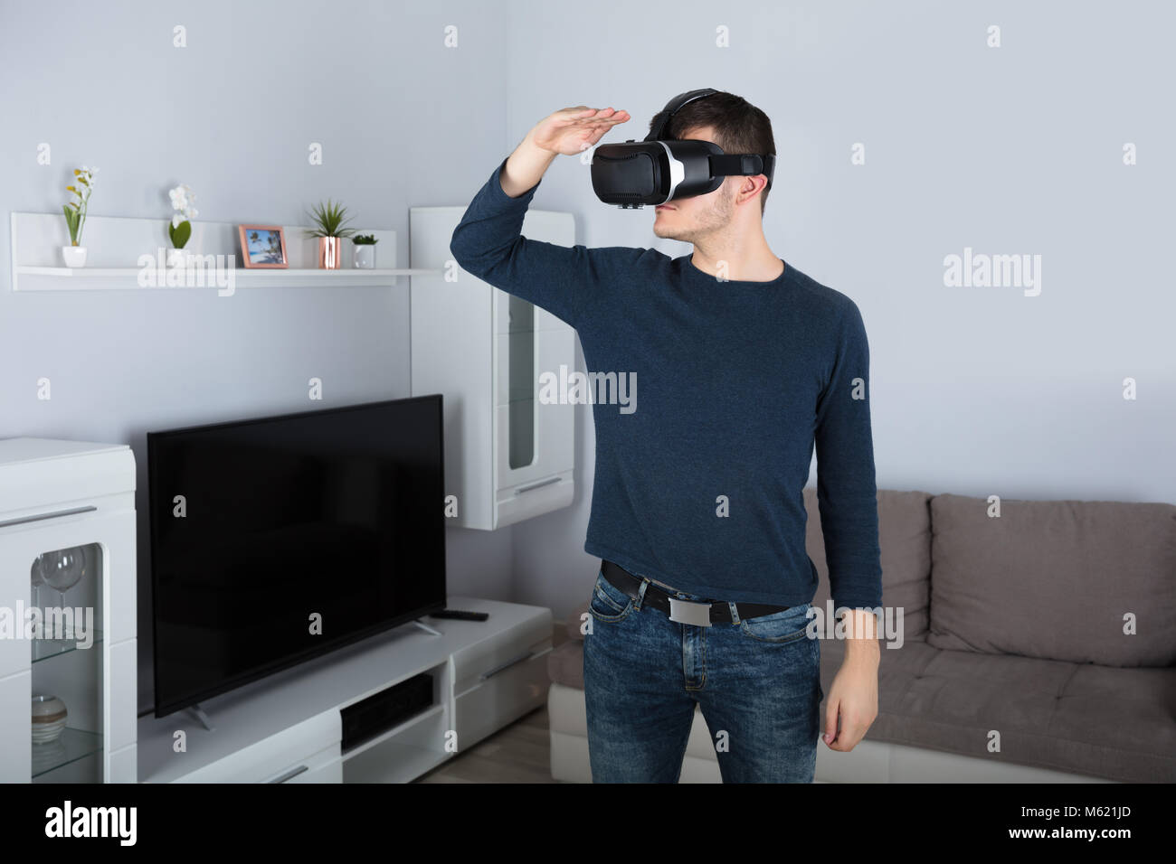 Portrait Of A Young Man Using Virtual Reality Headset With Hands Raised ...