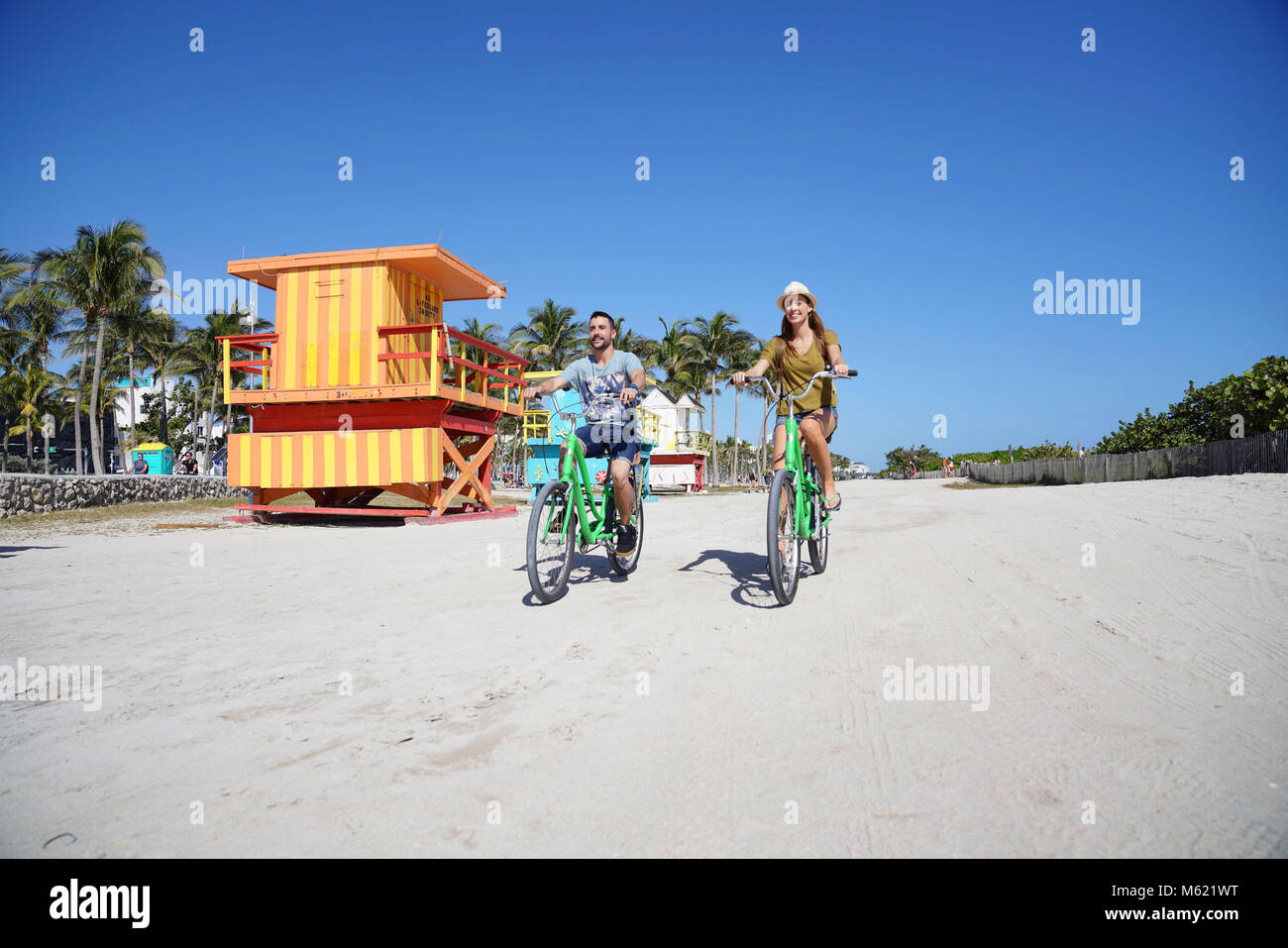 Couple of tourists riding bike in Miami beach Stock Photo - Alamy