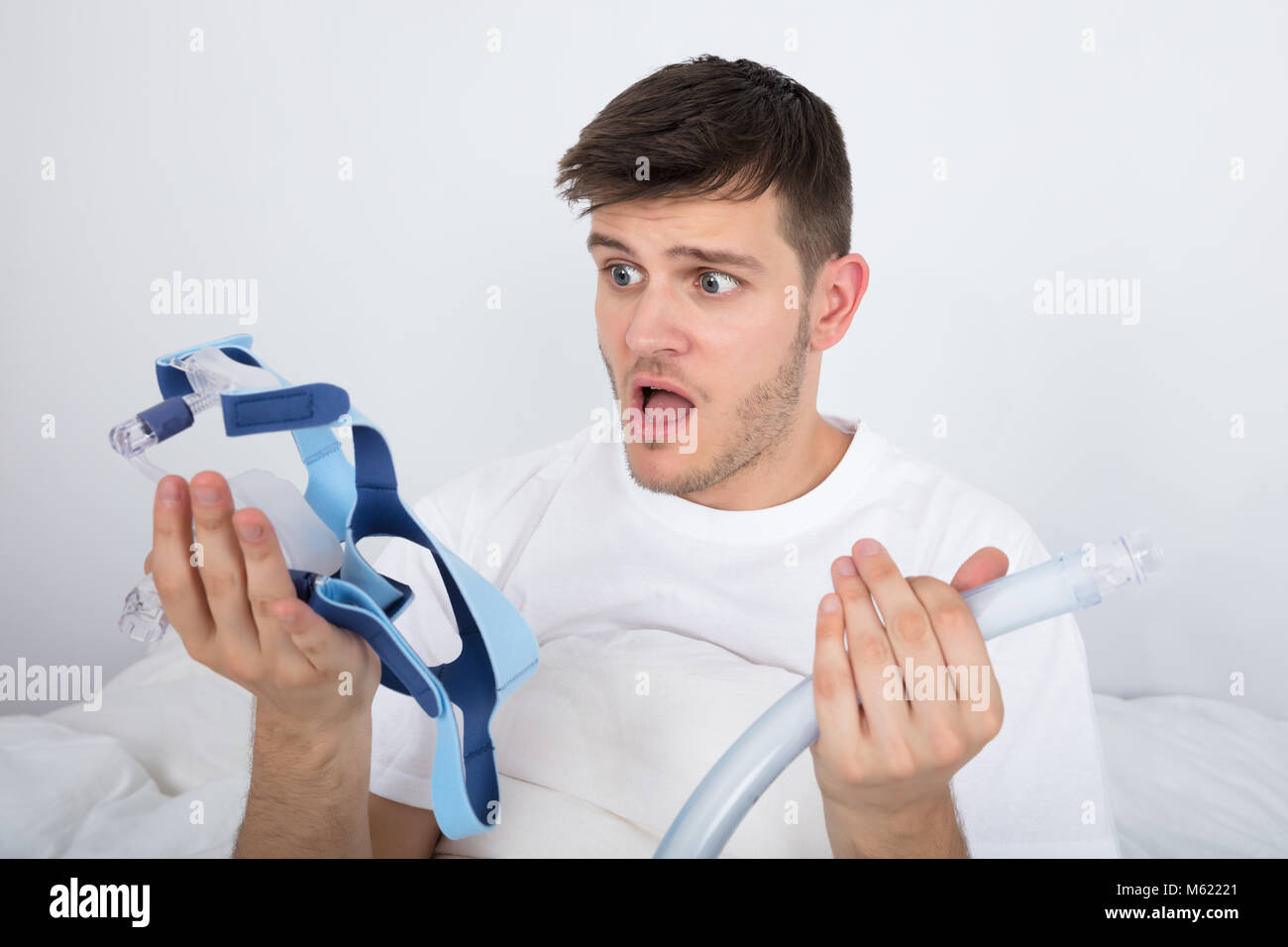 Worried Young Patient Looking At CPAP Machine On Bed Stock Photo - Alamy