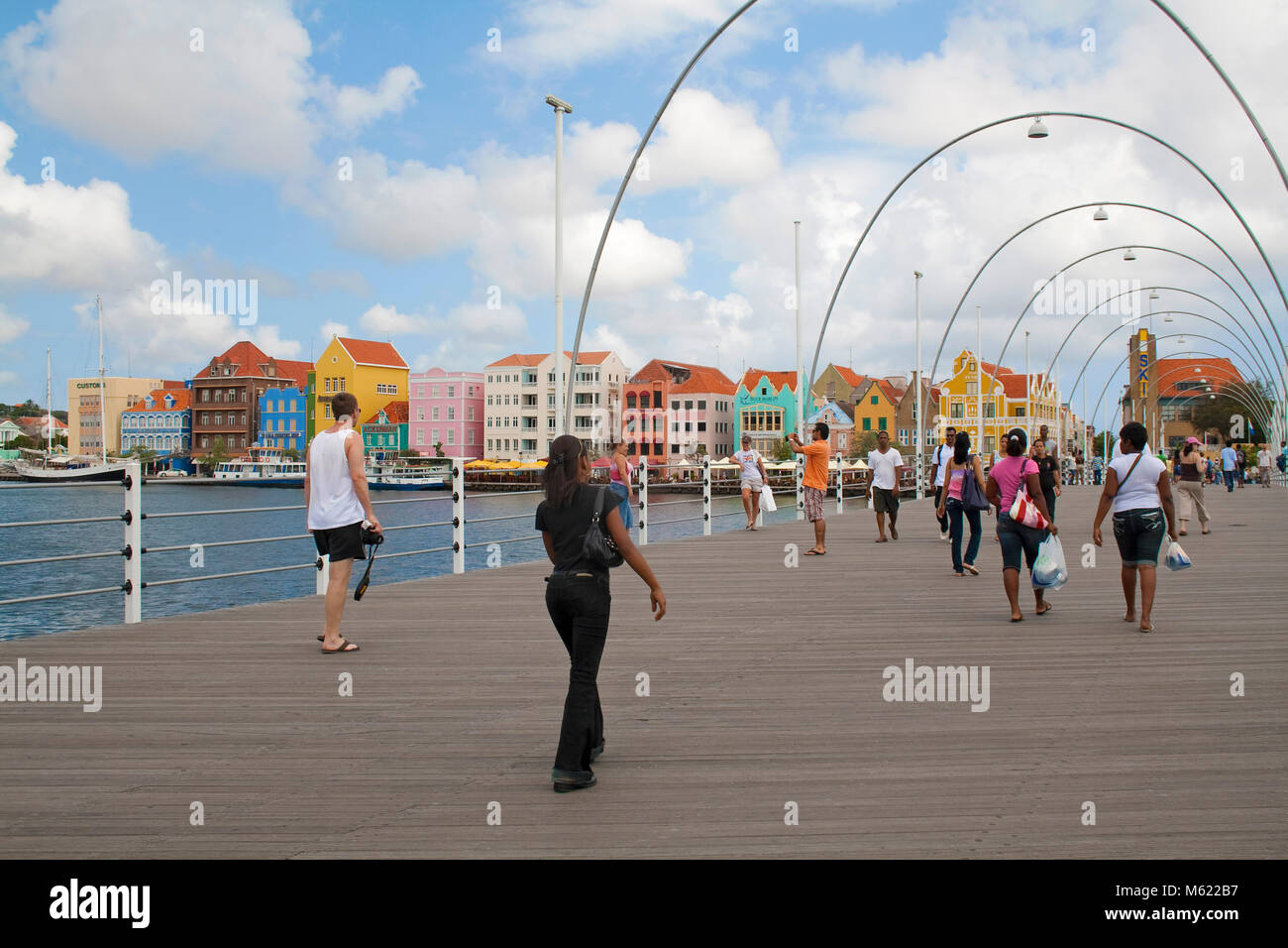 People on Queen Emma bridge, behind the trade arcade, colourful row of ...