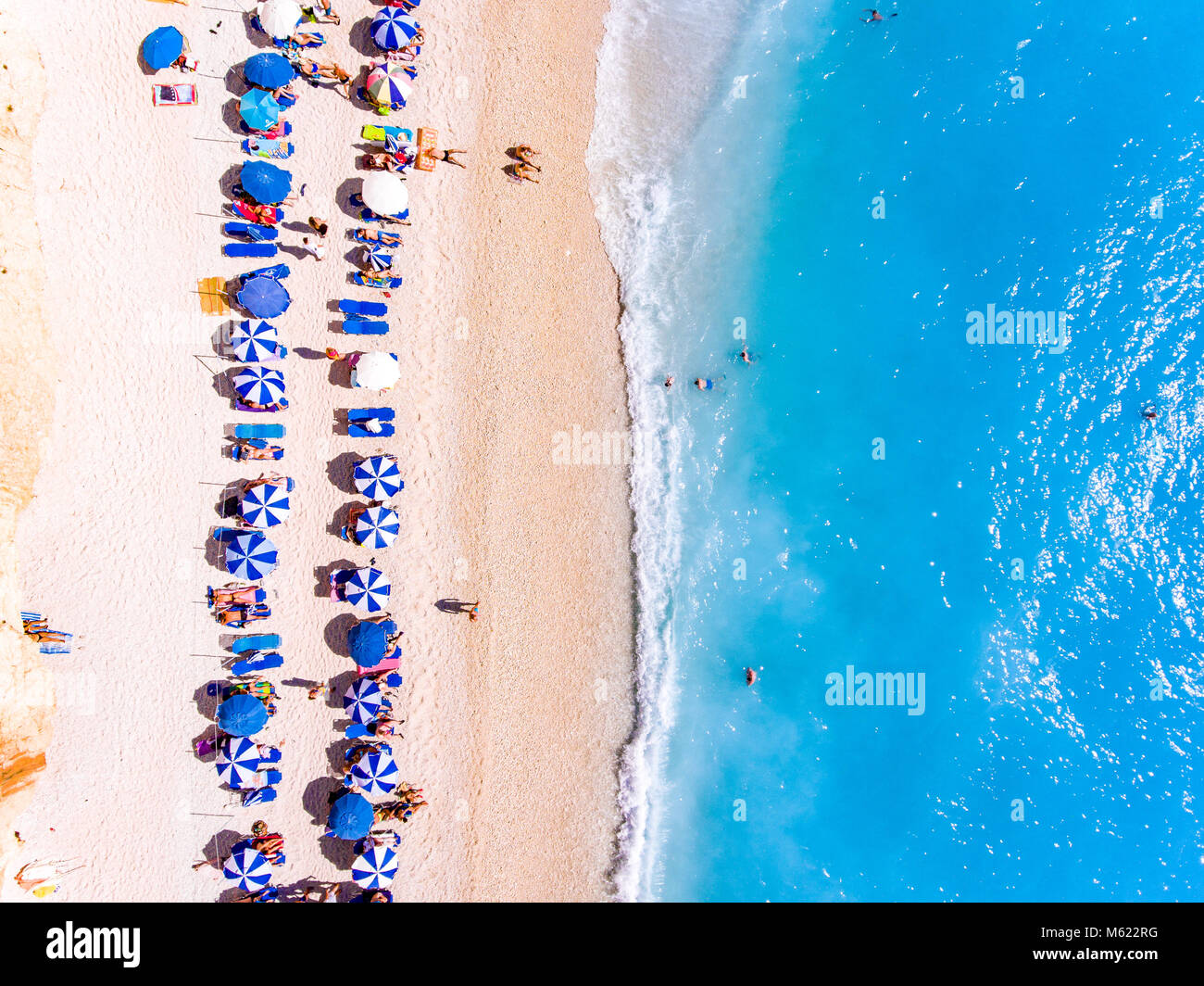 Top down view of a beach with tourists suntbeds and umbrellas with sand ...