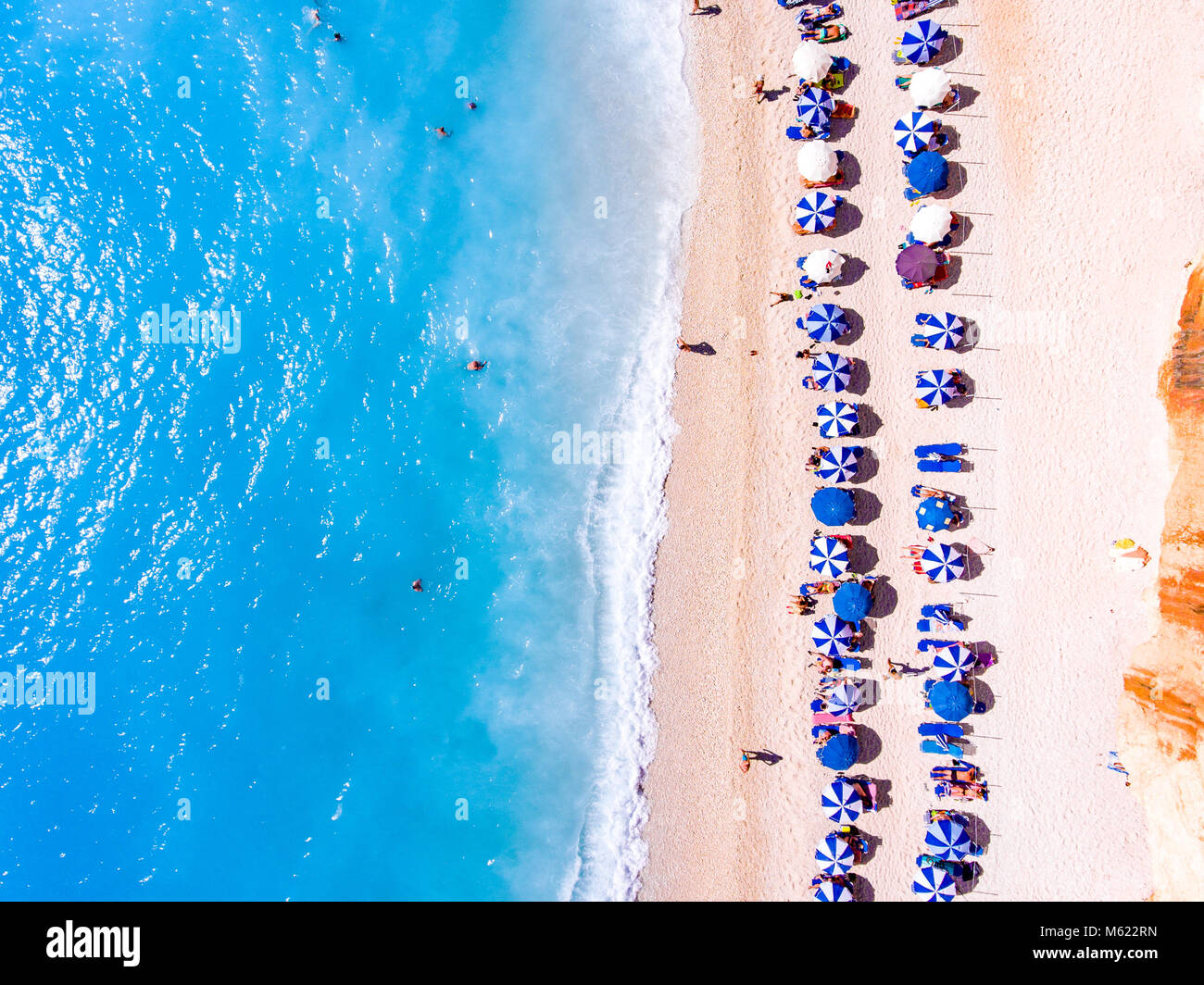 Top down view of a beach with tourists suntbeds and umbrellas with sand ...