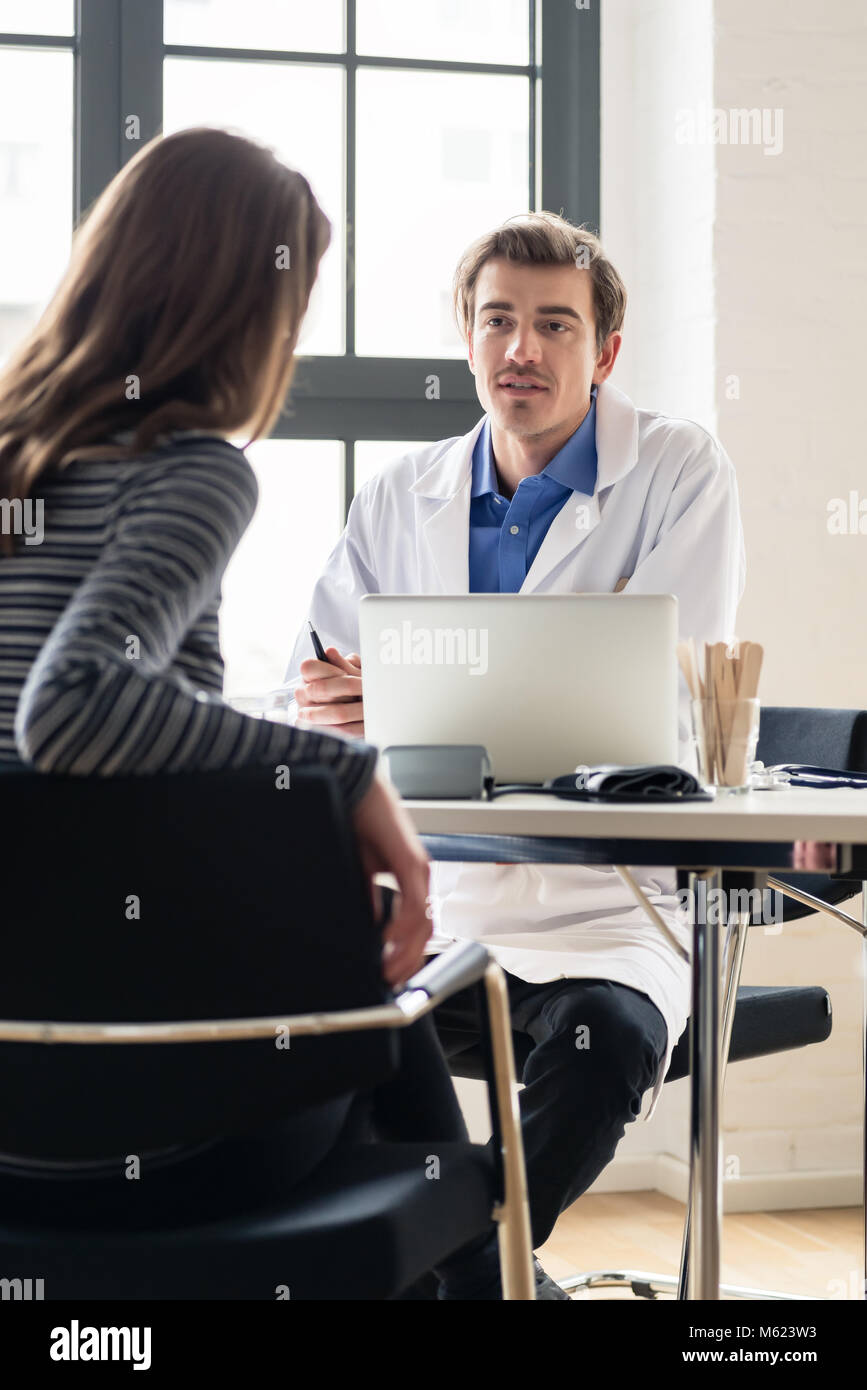 Young physician listening to his patient with respect and dedication ...