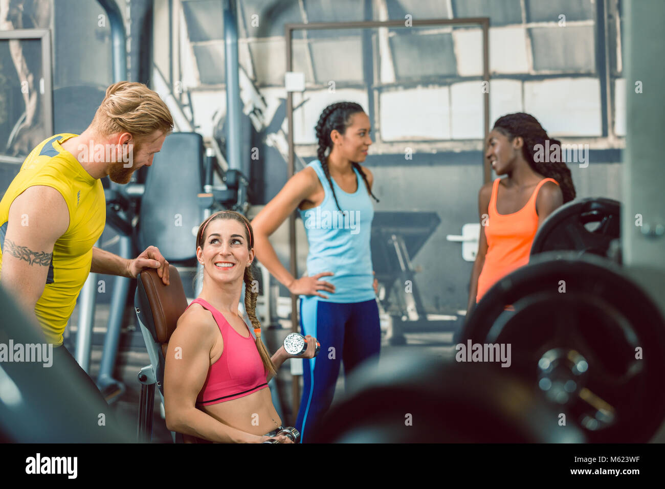 Side view of a handsome personal trainer guiding his client at the gym ...