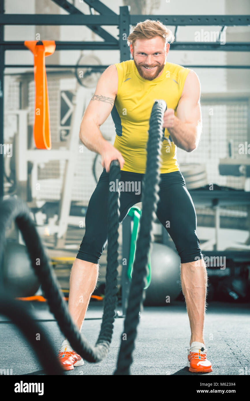 Handsome bodybuilder exercising with battle ropes during functional ...