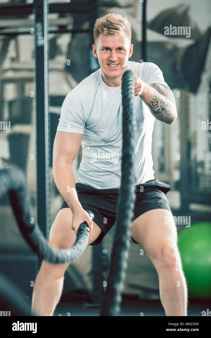 Handsome bodybuilder exercising with battle ropes during functional ...