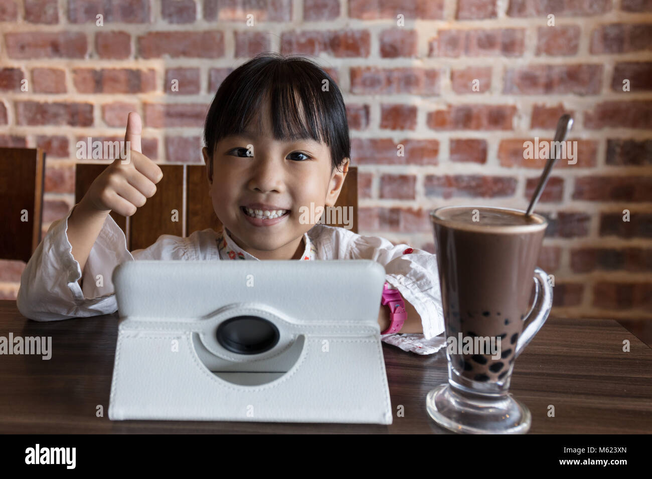 Asian Chinese little girl playing tablet computer at indoor cafe Stock ...