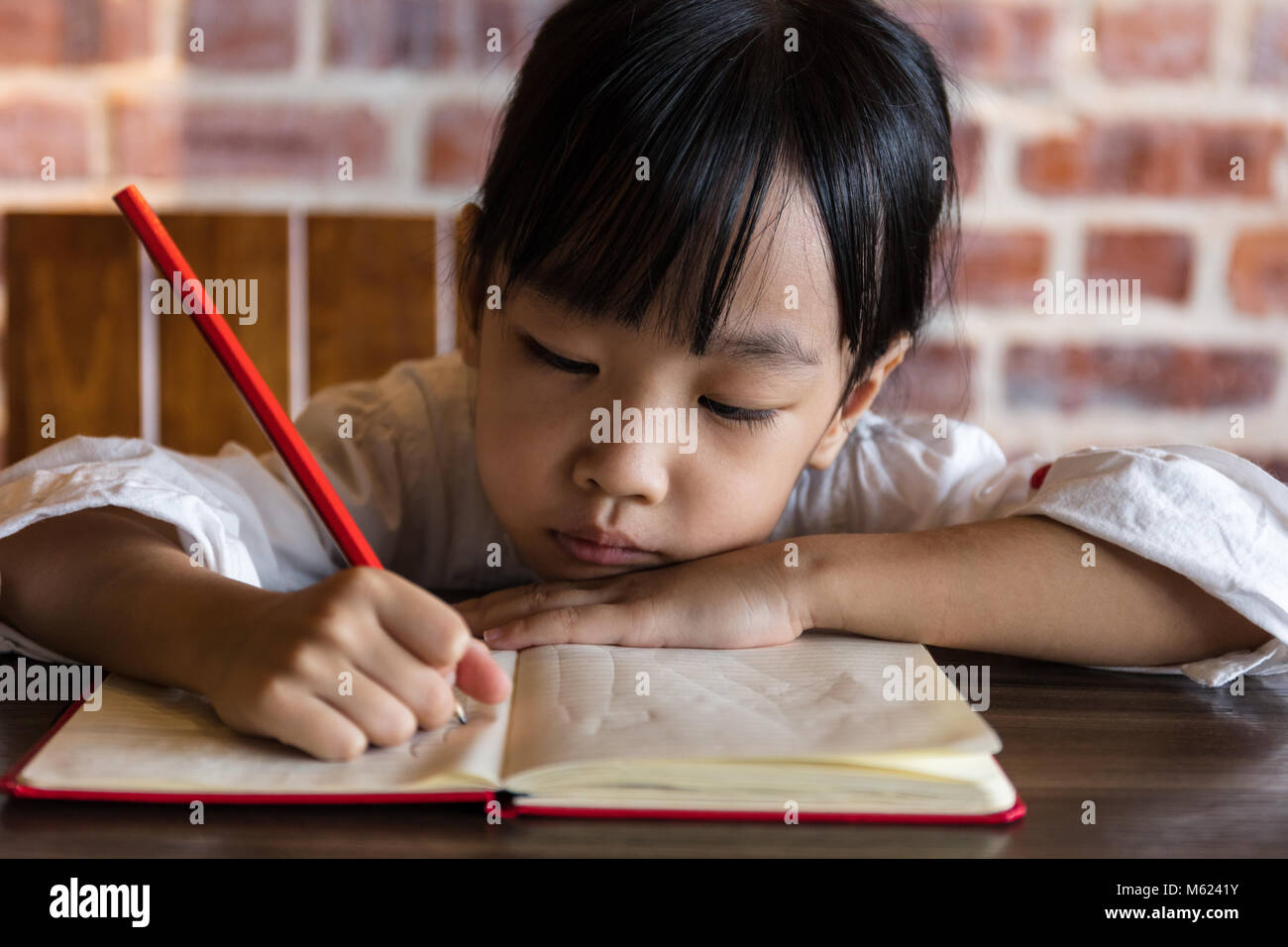 Asian Chinese little girl doing homework at indoor cafe Stock Photo - Alamy